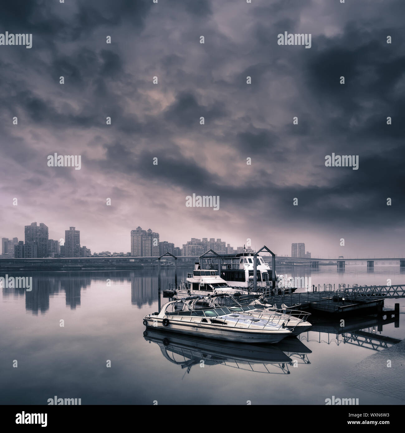 Cityscape of harbor with boat on water against dramatic sky Stock Photo ...
