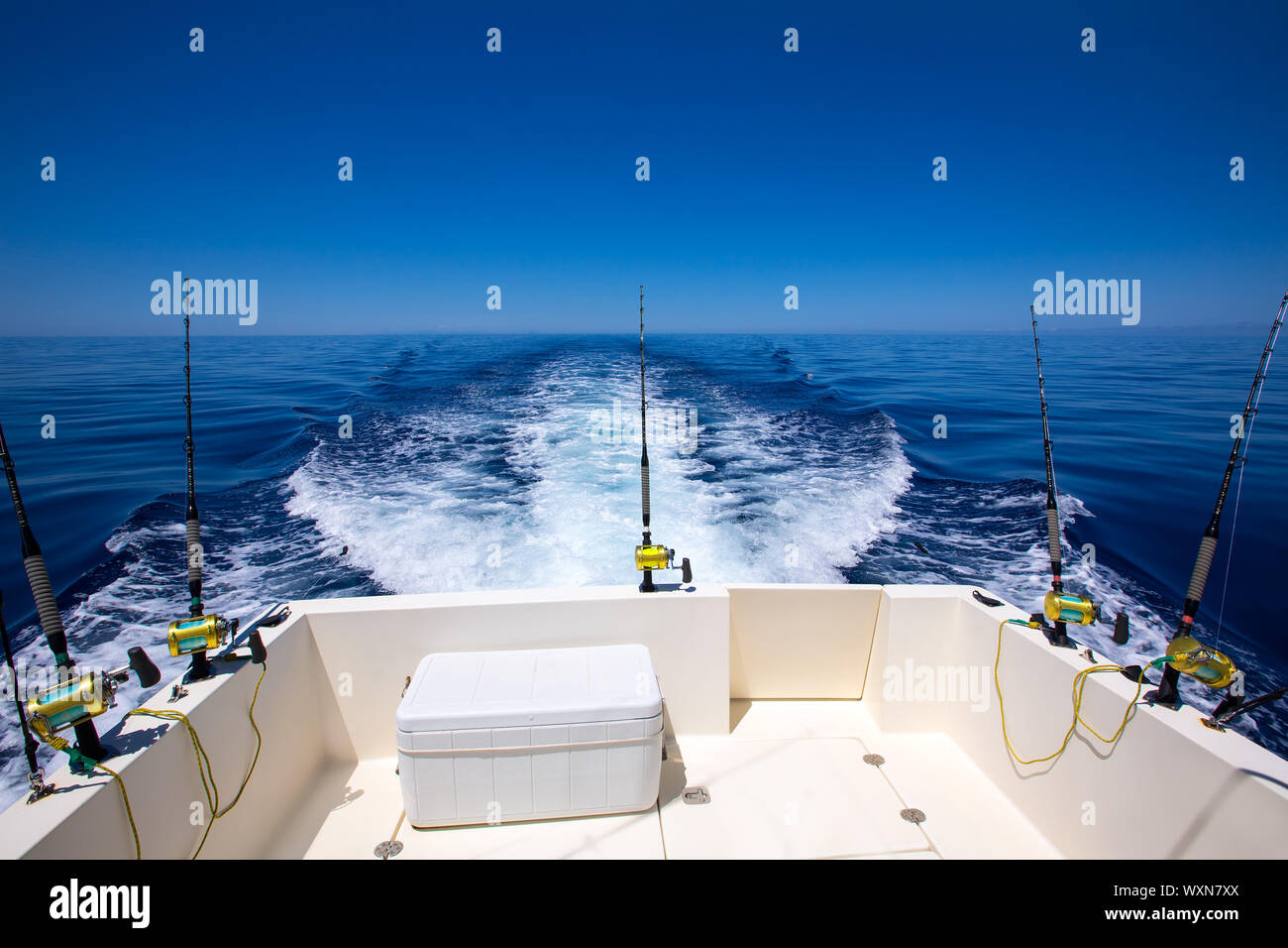 Fishing boat stern deck with trolling fishing rods and reels in blue ...