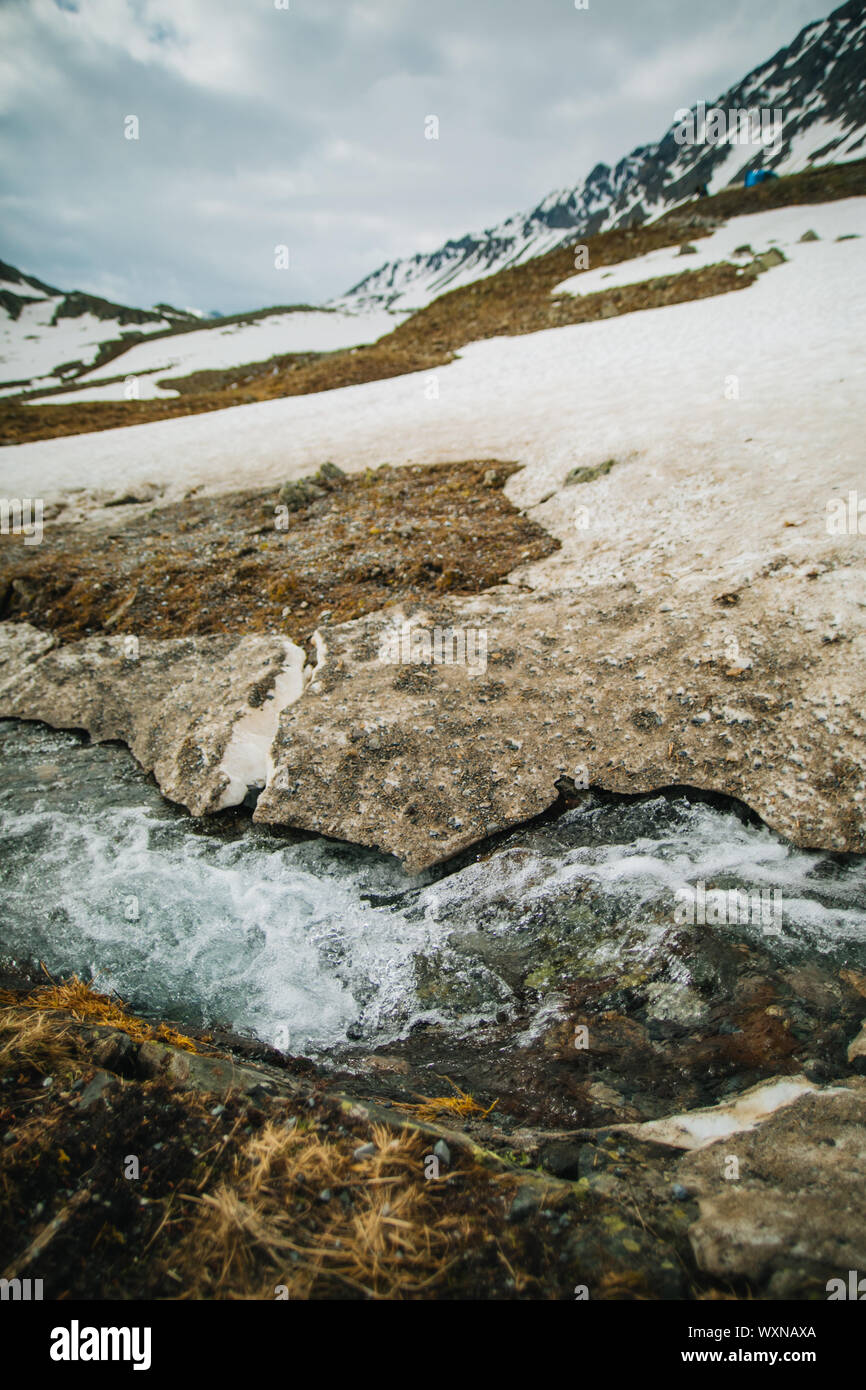 The detailed look at water runs under ice in a river. The snow is ...