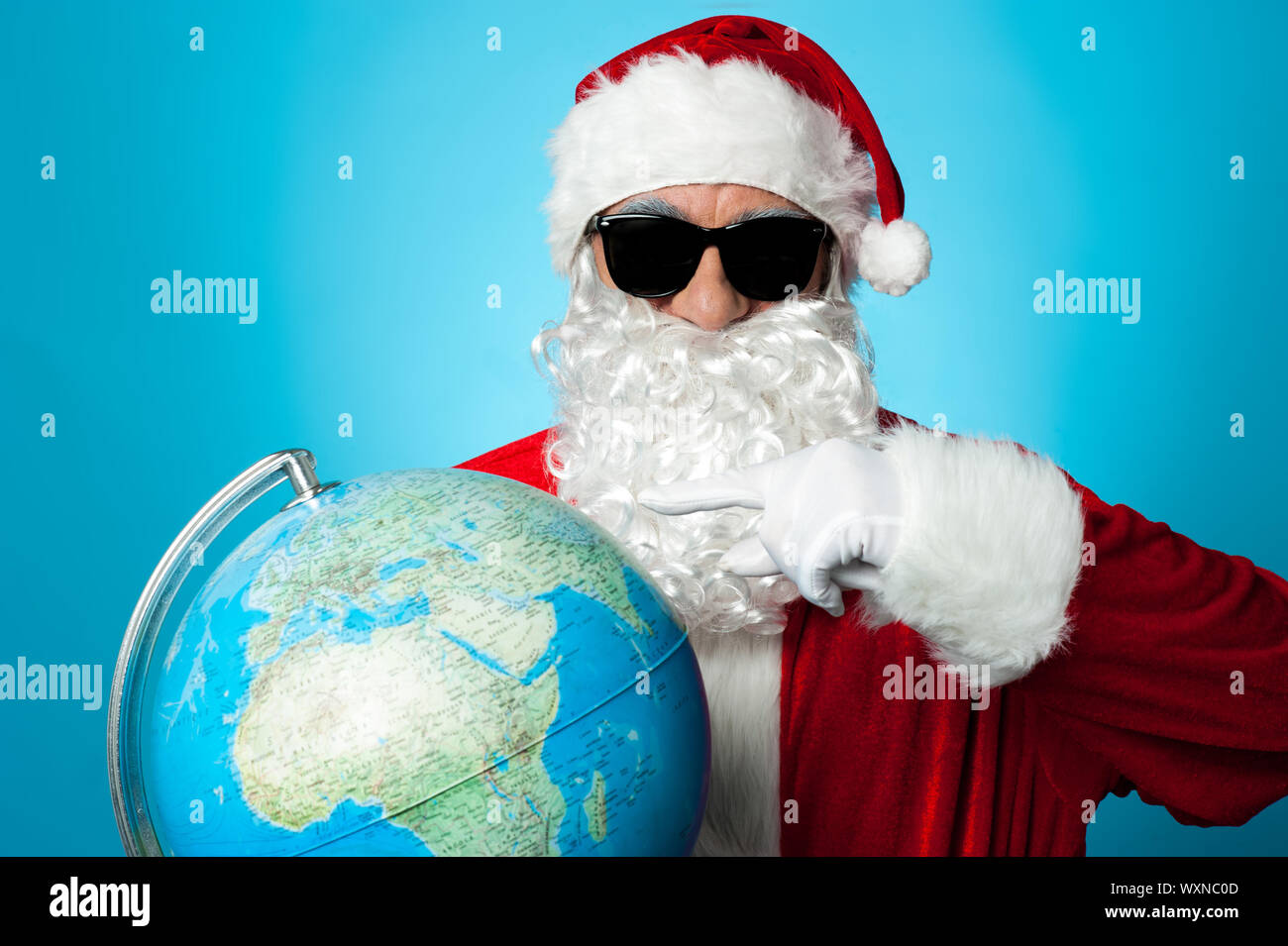 Modern santa in dark shades holding globe Stock Photo - Alamy