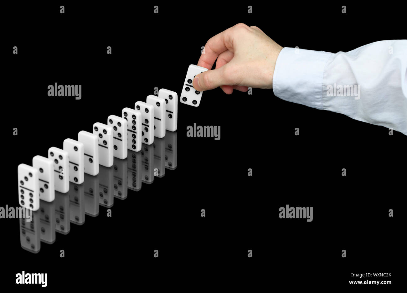 Hand building a line from dominoes on a black background Stock Photo ...