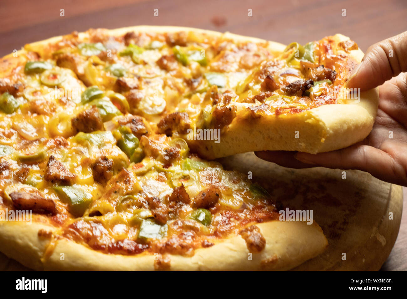 Pan Pizza slice take from hand side view with dark brown wood Stock ...
