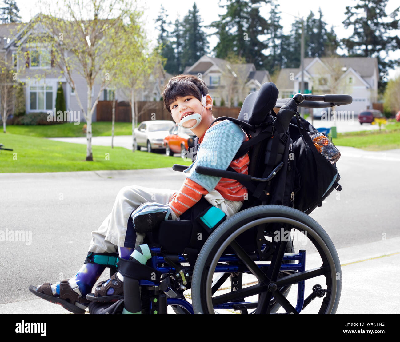 Happy disabled six year old boy waiting on sidewalk in wheelchair ...