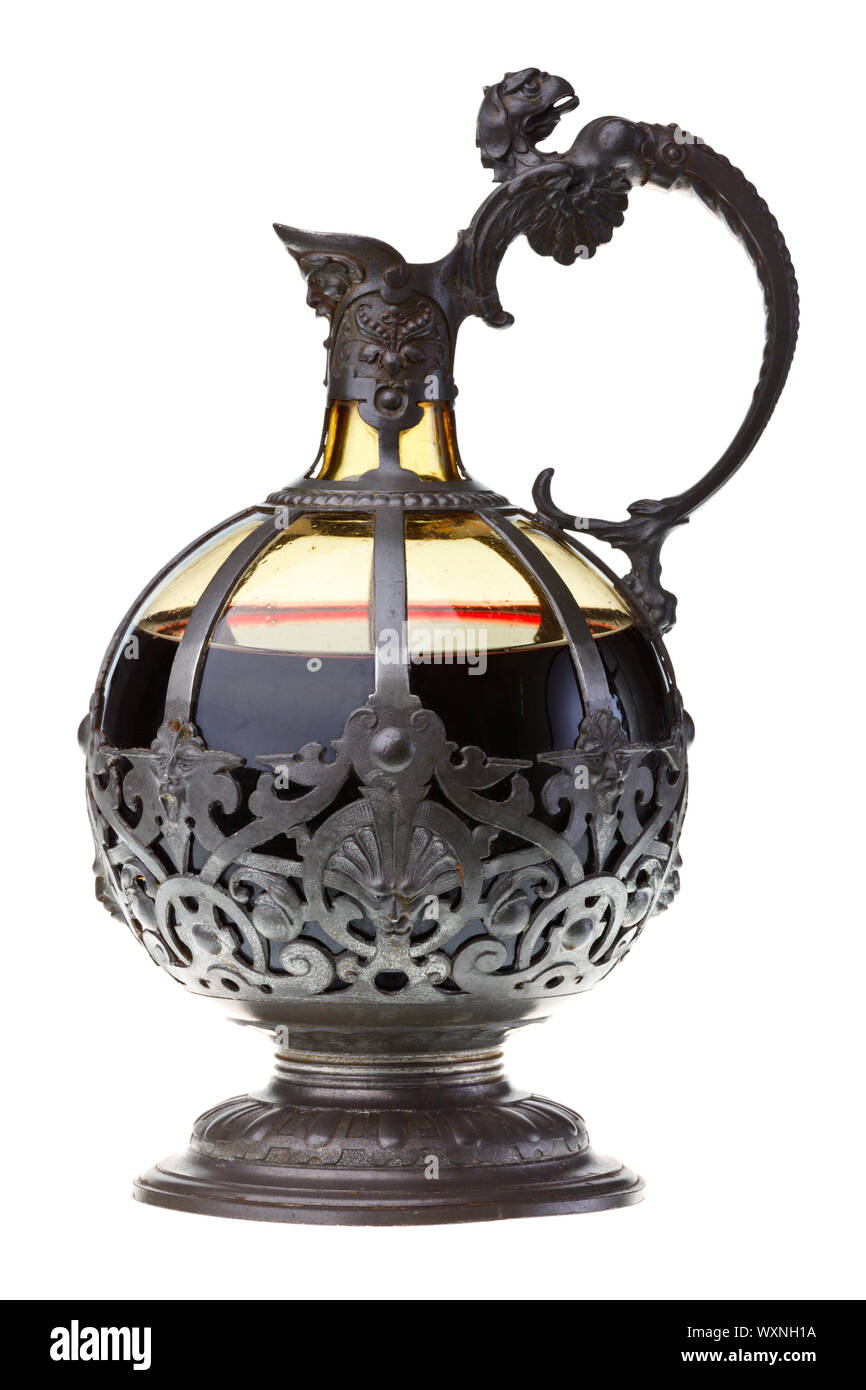 Old glass metal claret jug decanter with red wine on white background ...