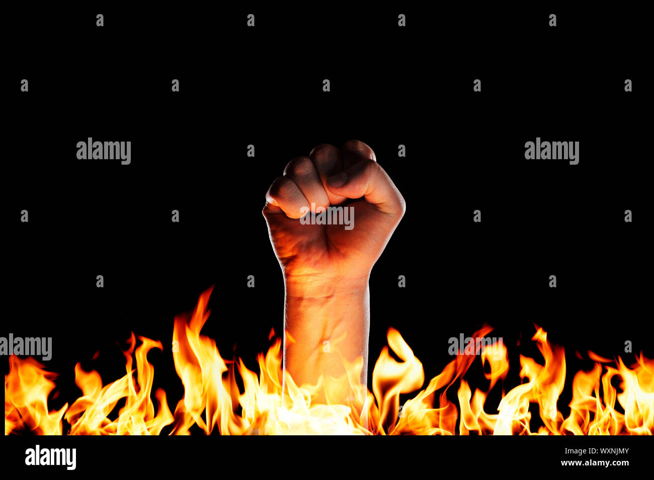 Hand in a fist emerging from a sea of fire Stock Photo - Alamy