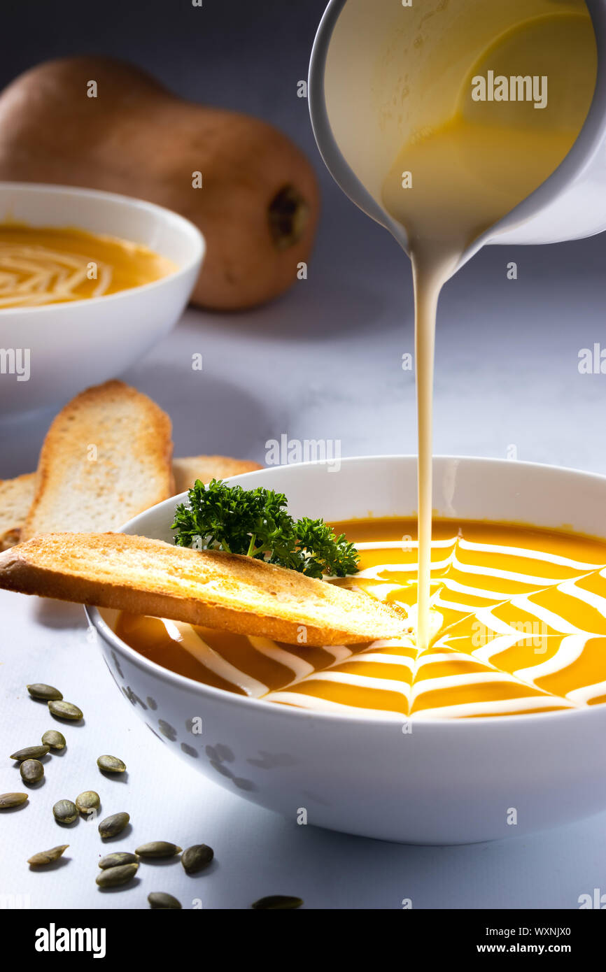 Pumpkin soup with cream pour Stock Photo - Alamy