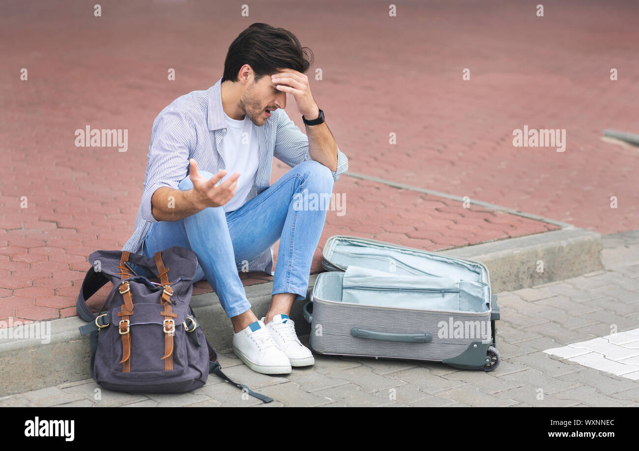 Sad man sitting at international airport with luggage Stock Photo - Alamy
