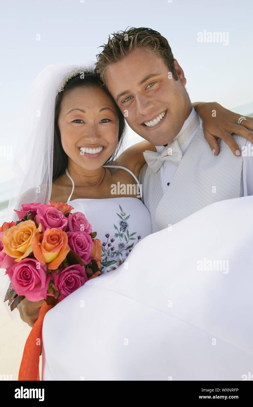 Groom Carrying Bride on Beach Stock Photo - Alamy