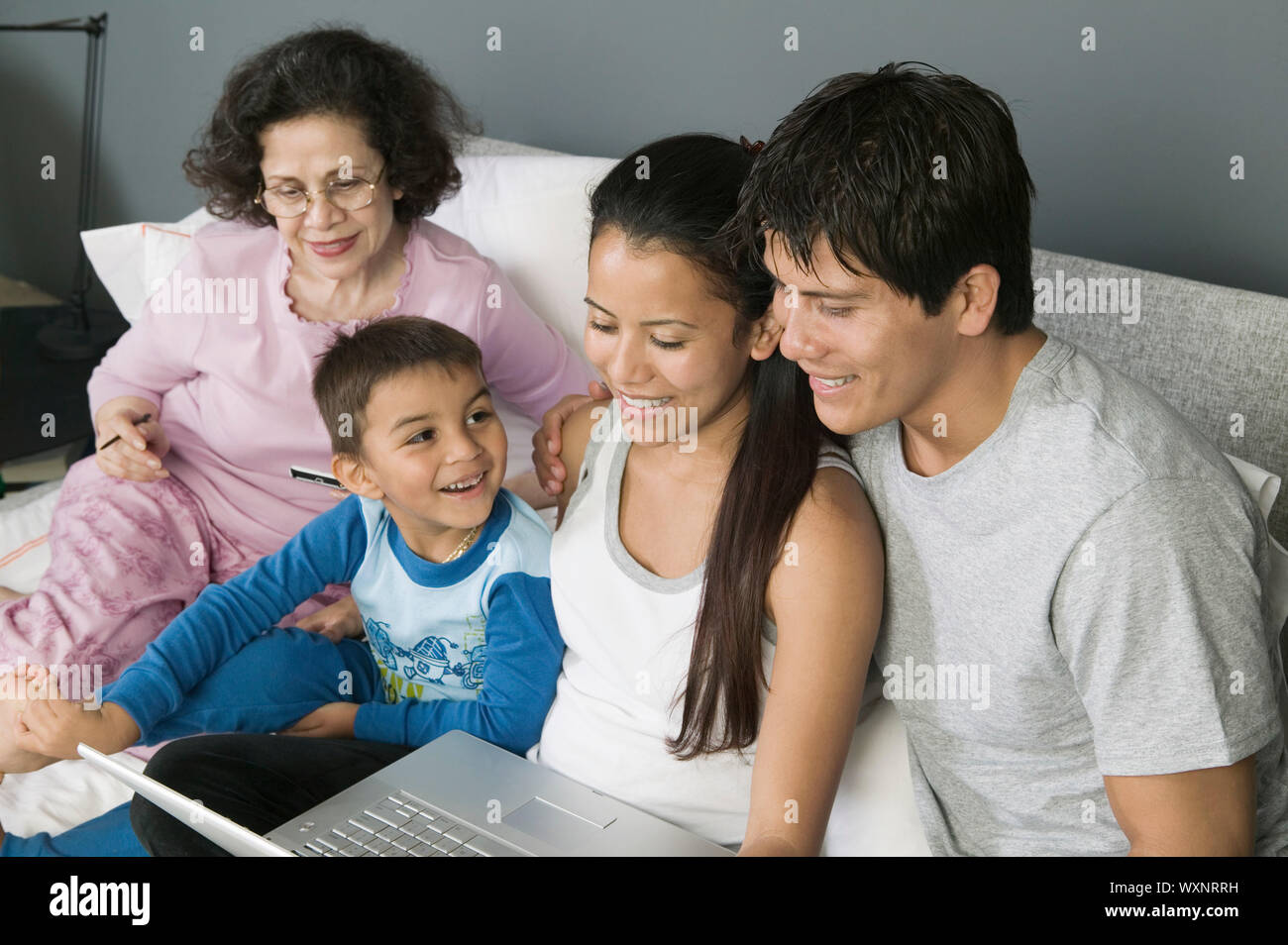 Family Using Laptop on Couch Stock Photo - Alamy