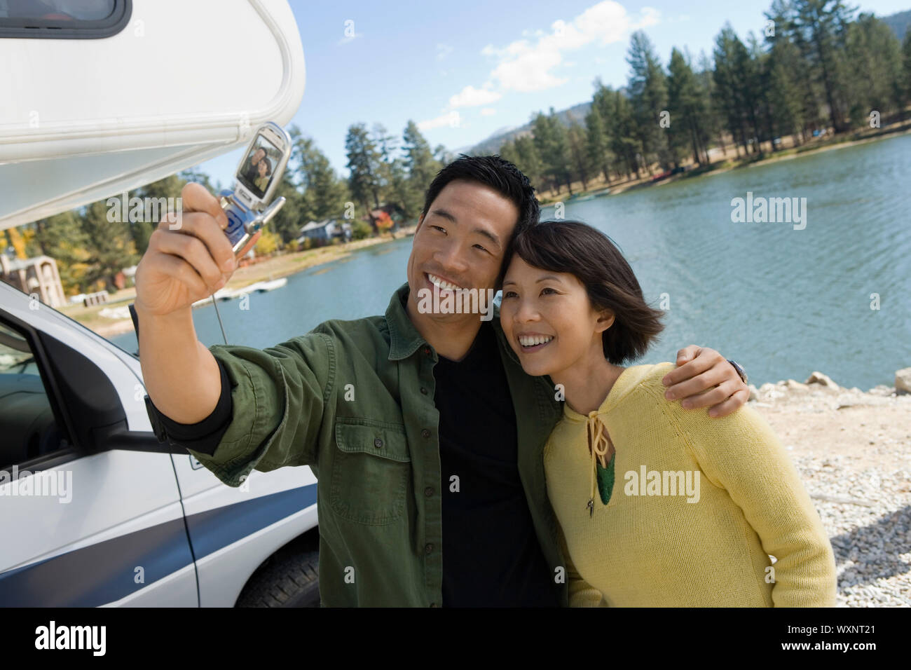 Couple Using Cell Phone Camera at Lake Stock Photo - Alamy