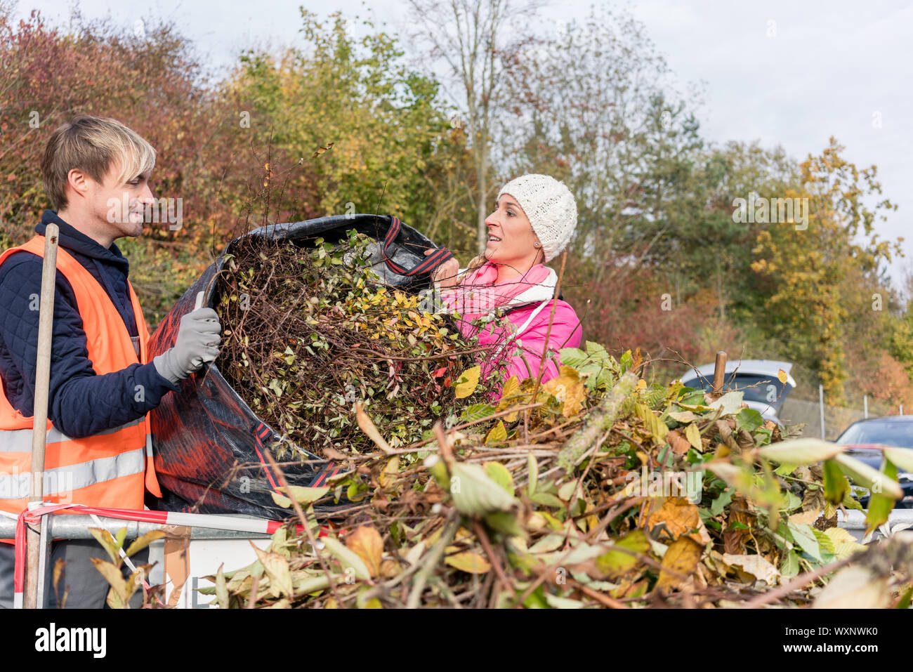 Woman and man putting waste green in container on recycling center ...