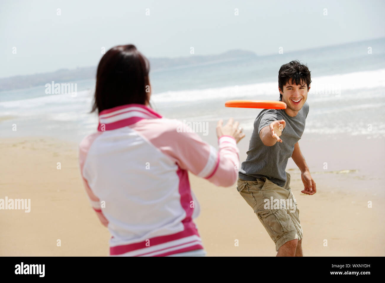 Couple Playing Frisbee on Beach Stock Photo - Alamy