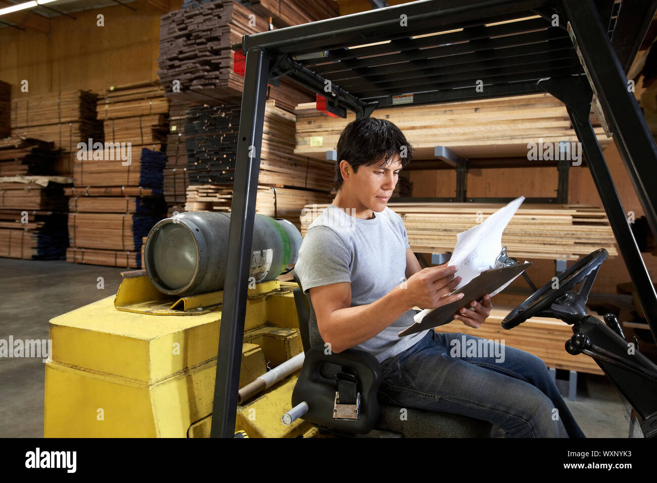 Forklift Driver in Warehouse Looking at Paperwork Stock Photo - Alamy