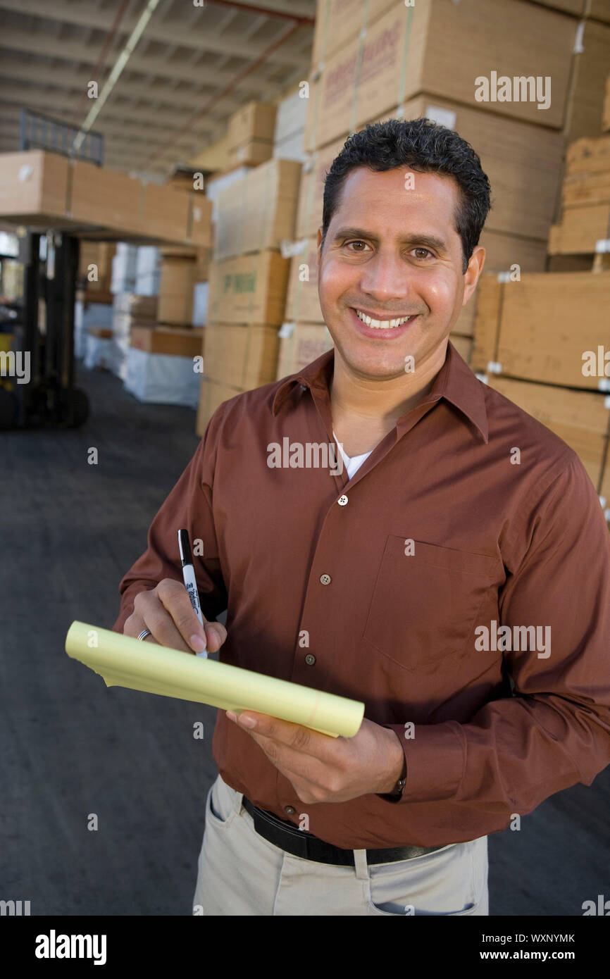 Mid-adult man stock-taking in warehouse Stock Photo - Alamy