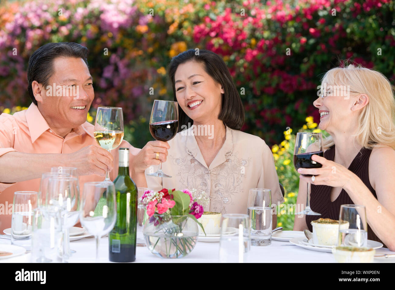 Three friends toasting at outdoor table Stock Photo - Alamy
