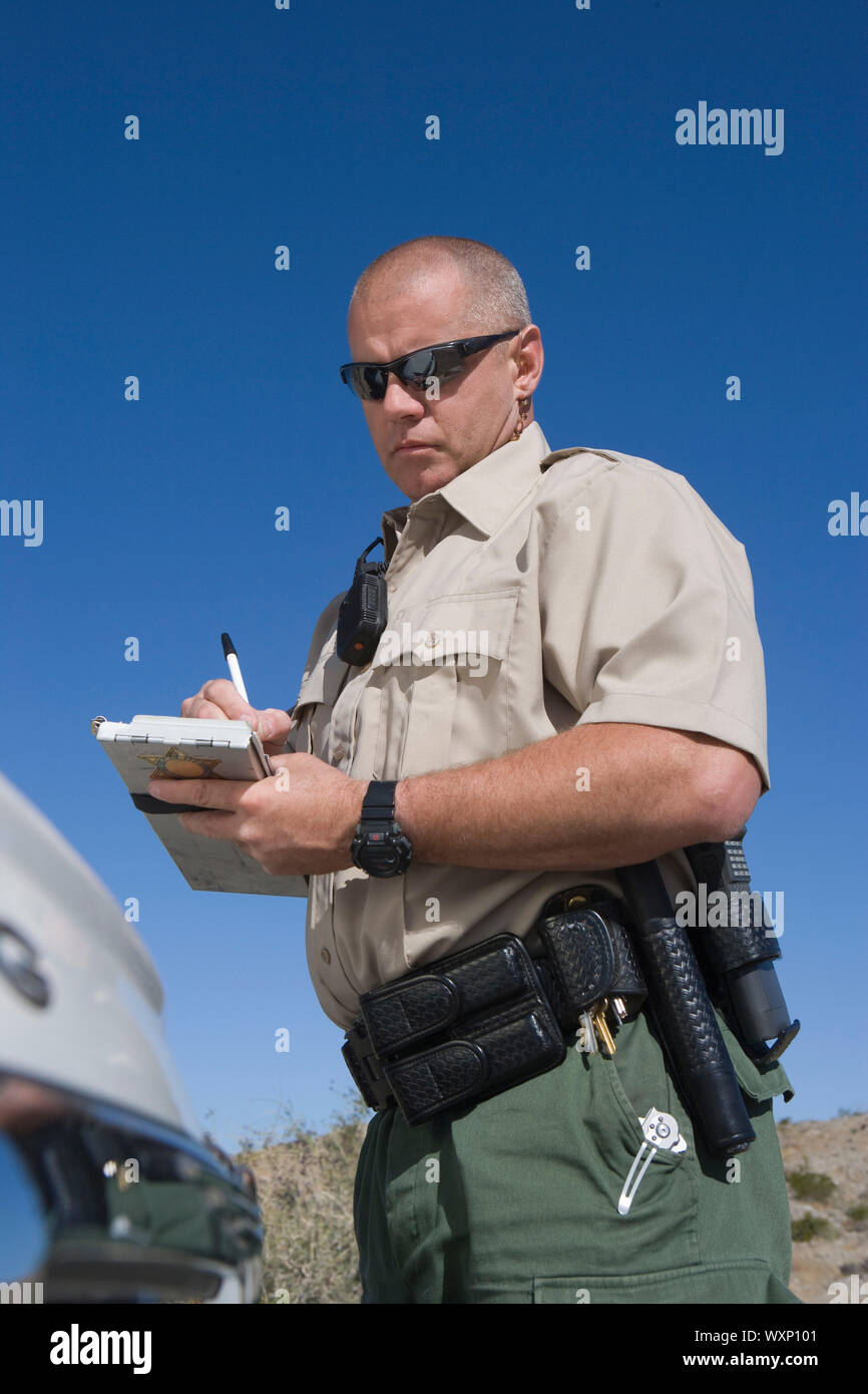Policeman writing speeding ticket Stock Photo - Alamy