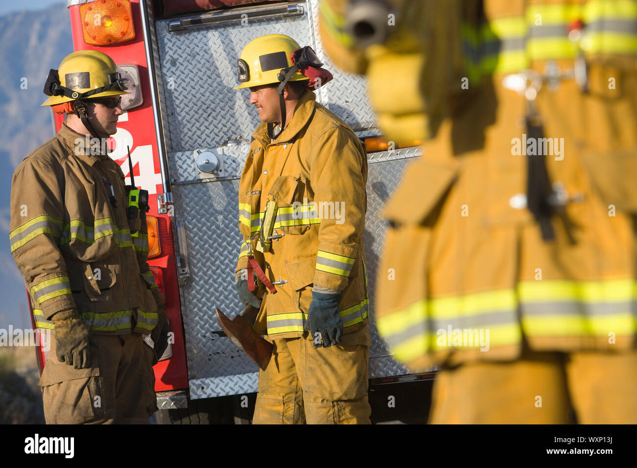 Firefighters by fire engine Stock Photo - Alamy