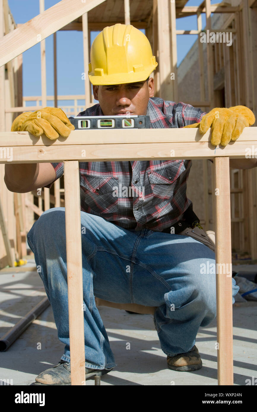 Construction worker using spirit level on building Stock Photo - Alamy
