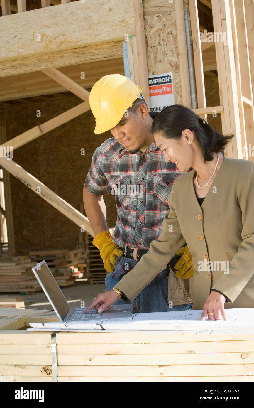 Construction worker using laptop with surveyor Stock Photo - Alamy