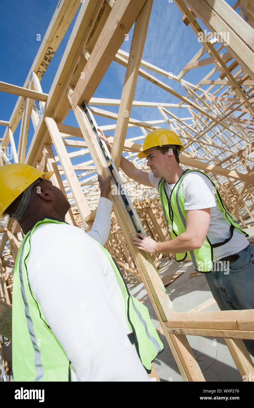 Two construction workers measuring building framework Stock Photo - Alamy