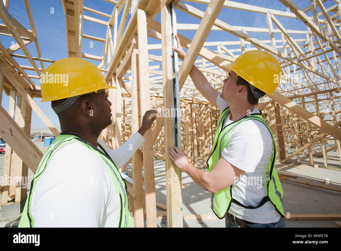 Two construction workers measuring building framework Stock Photo - Alamy