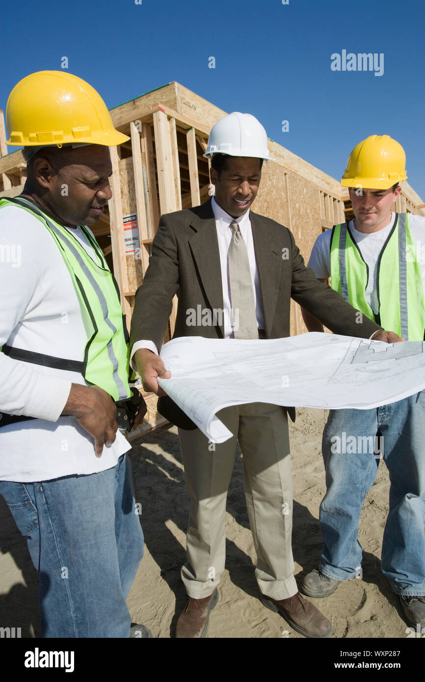 Two construction workers and surveyor studying blueprint Stock Photo ...