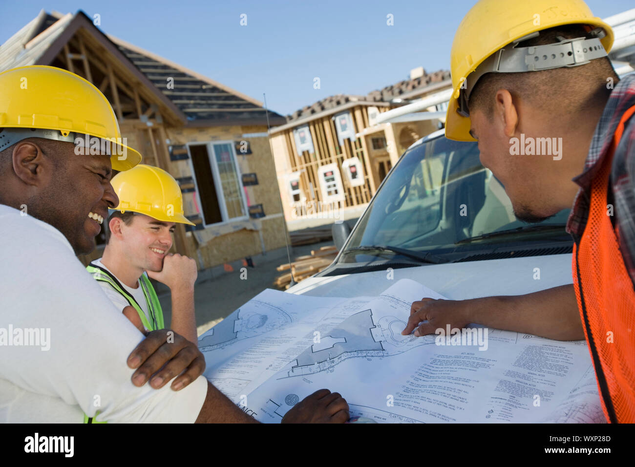 Three construction workers studying blueprint Stock Photo - Alamy