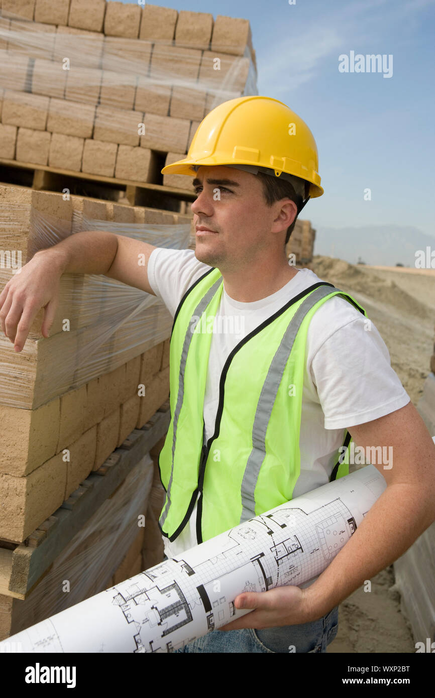 Construction worker holding blueprints on site Stock Photo - Alamy