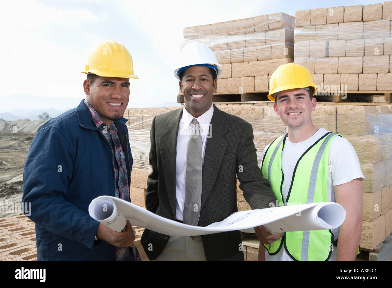 Three construction workers standing on construction site with ...