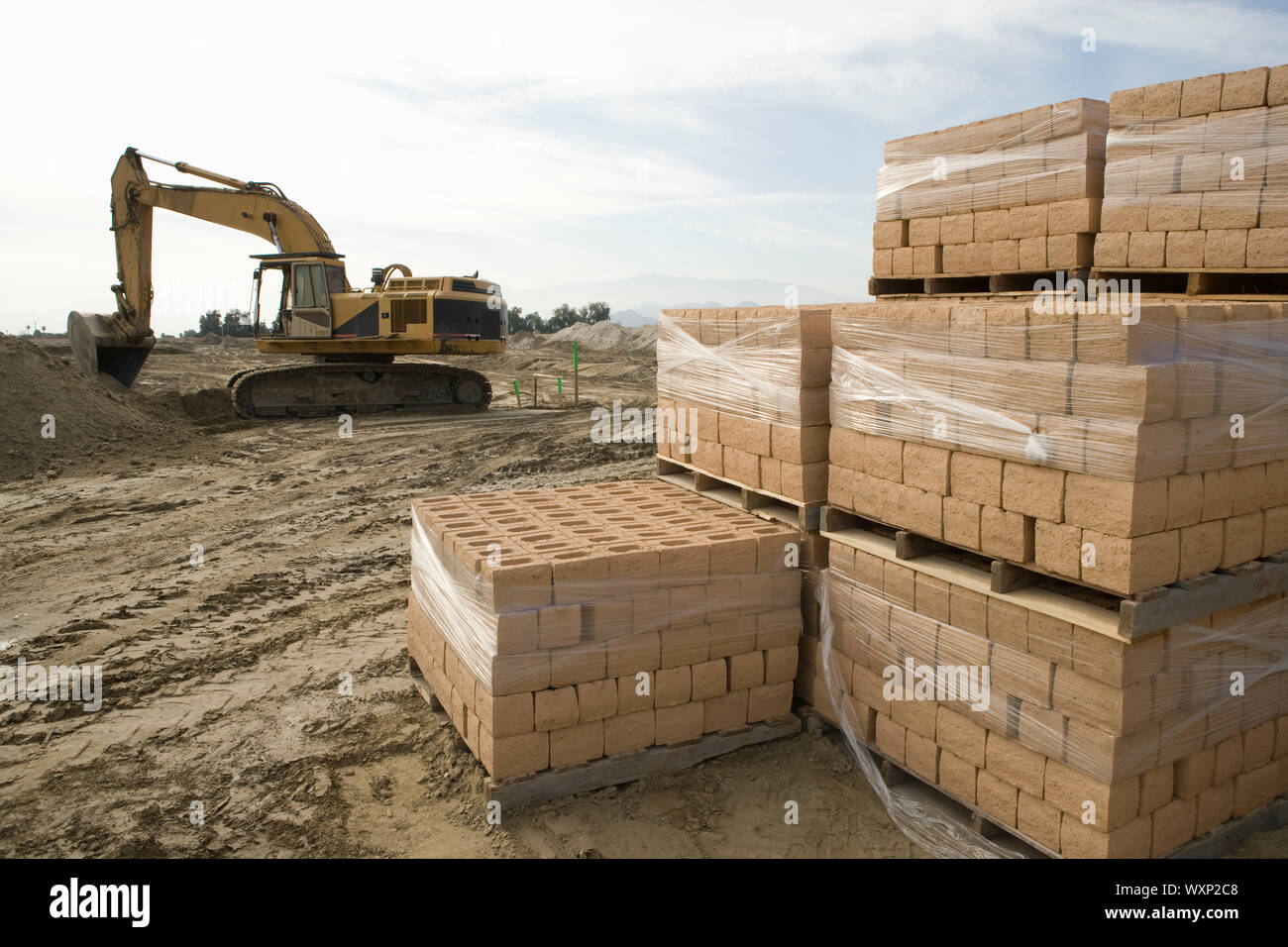 Digger and stacked bricks on construction site Stock Photo - Alamy