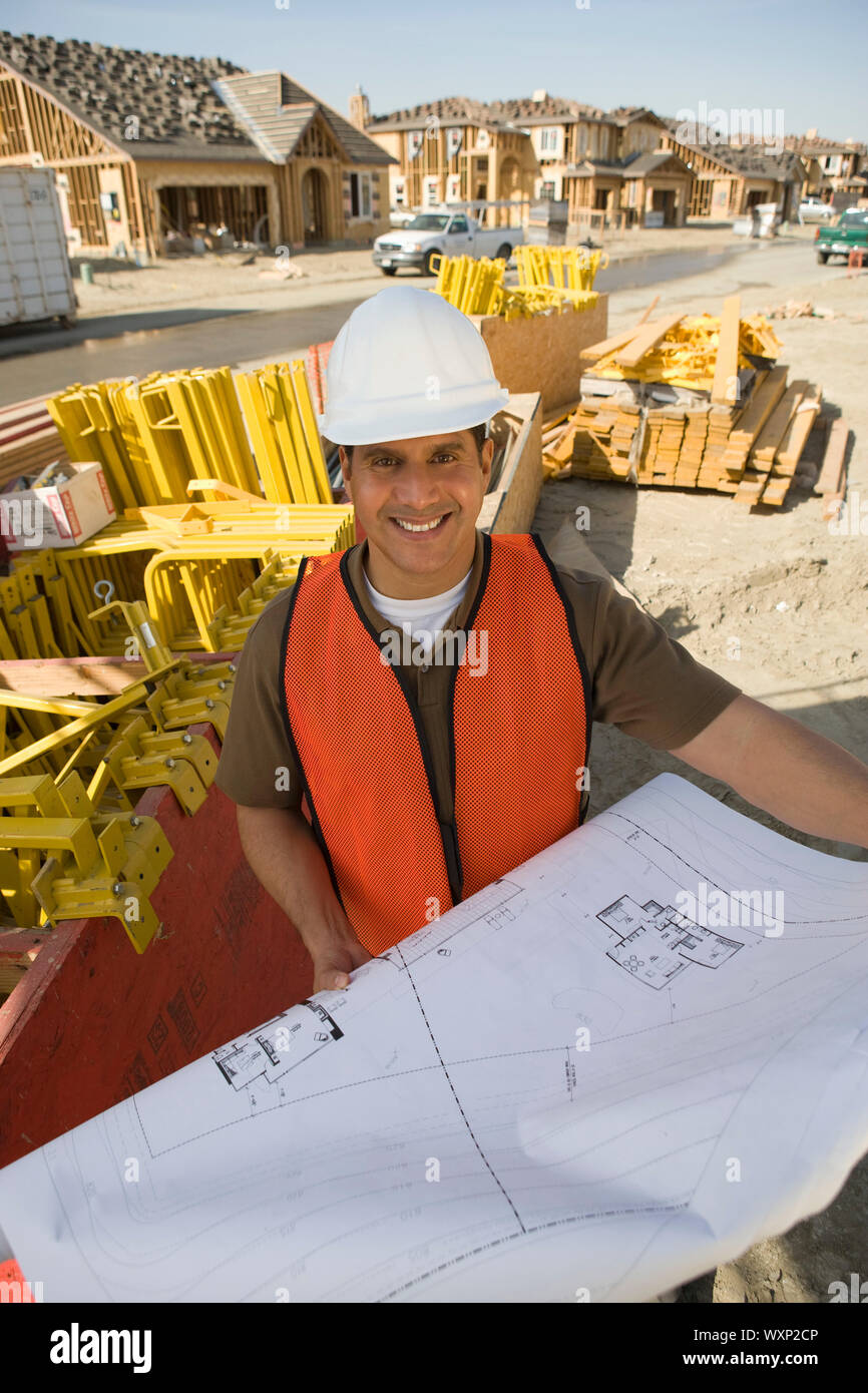 Construction worker standing on construction site and holding ...