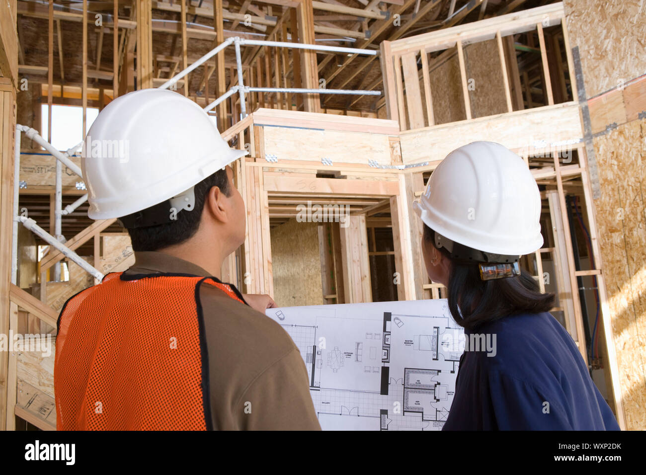 Architect and construction worker looking up while holding with ...