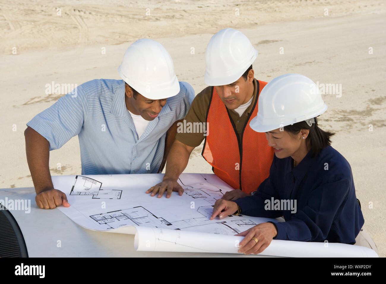 Architect and two construction workers looking at blueprints on ...