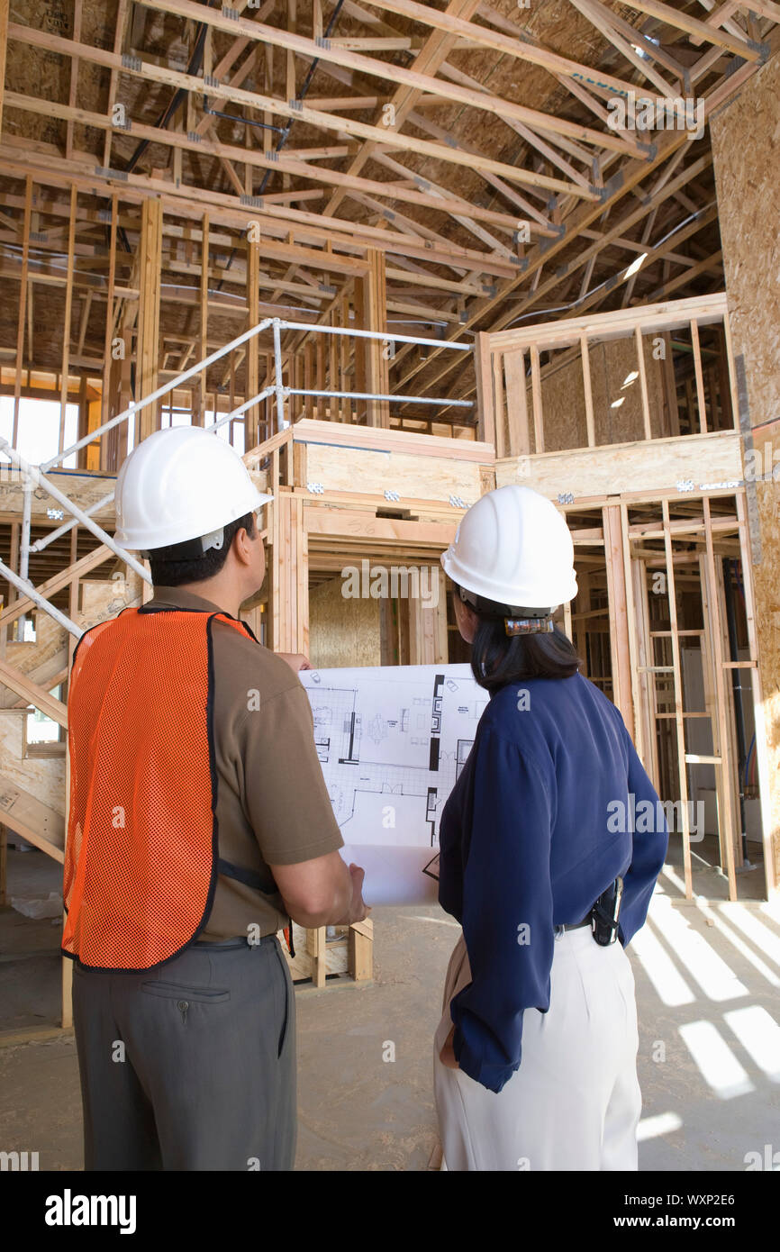 Architect and construction worker looking up while holding with ...