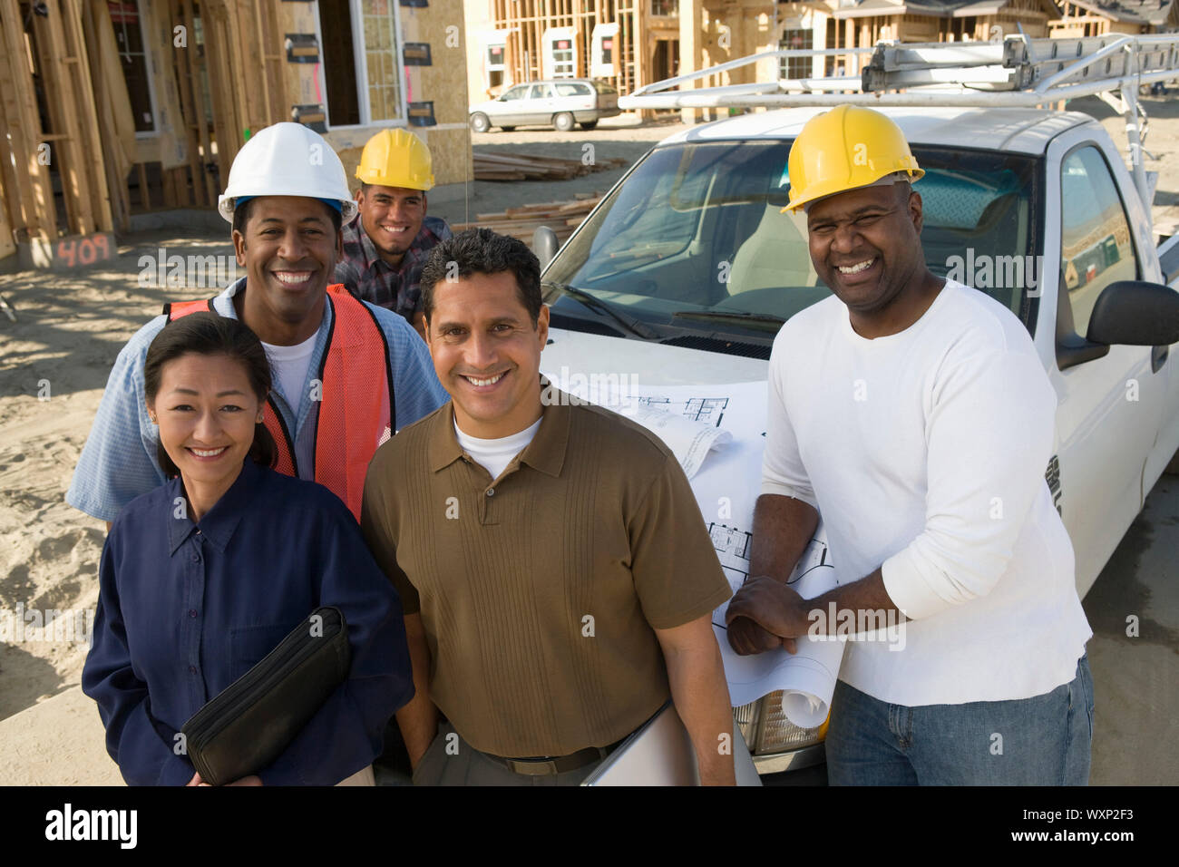 Architect and four construction workers standing in front of car on ...