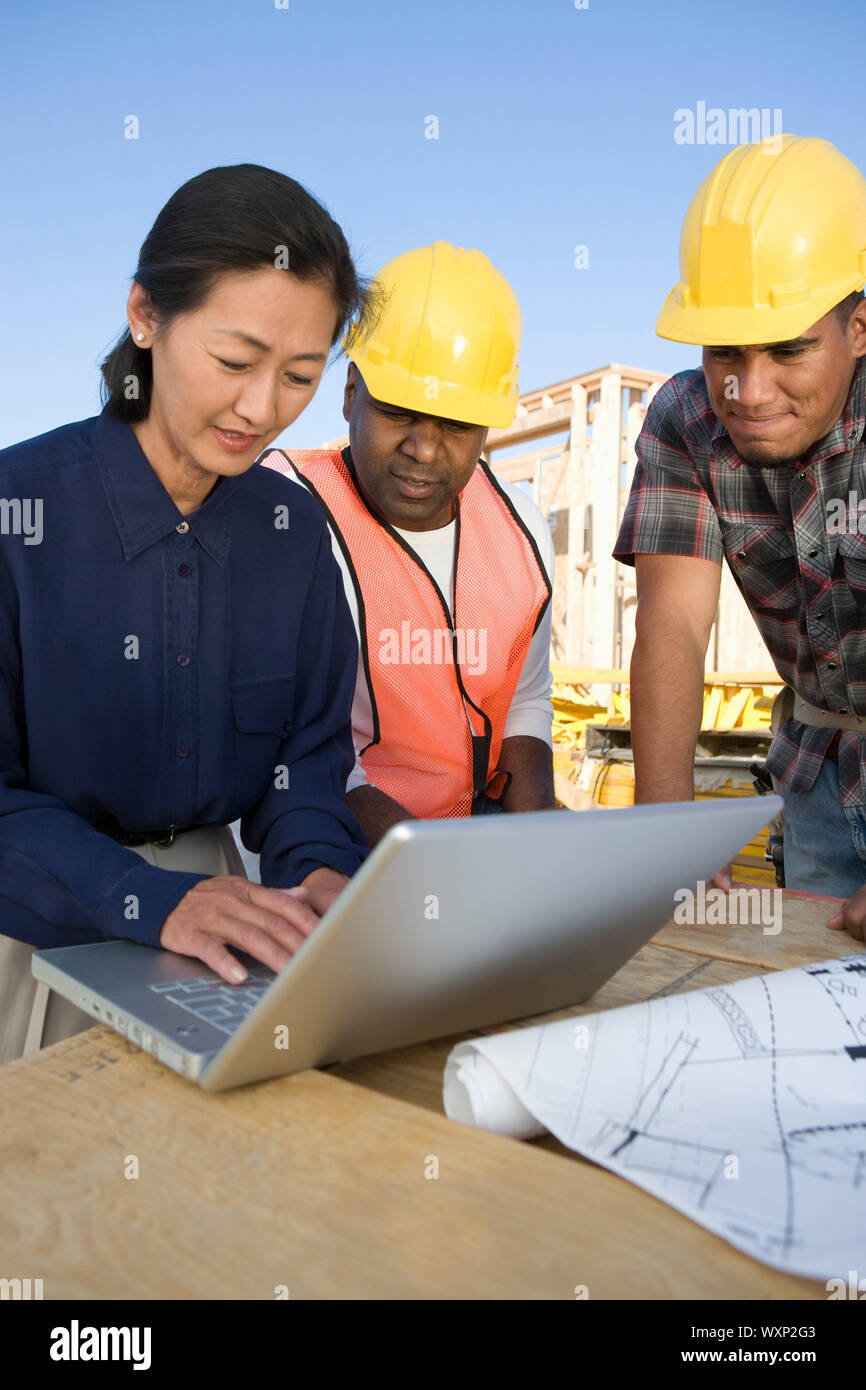 Architect and two construction workers using laptop Stock Photo - Alamy