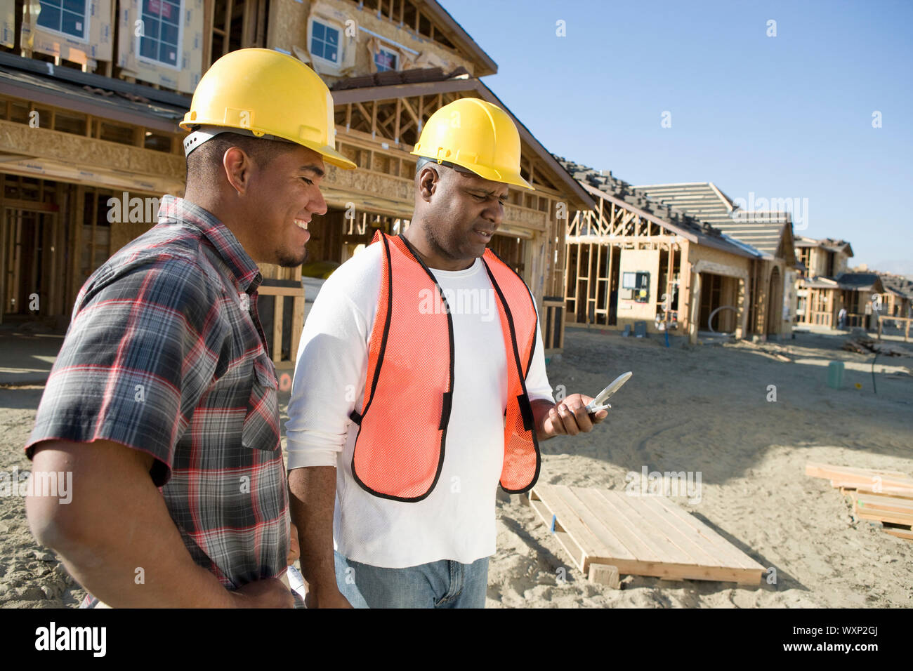 Two construction workers using mobile phone on construction site Stock ...