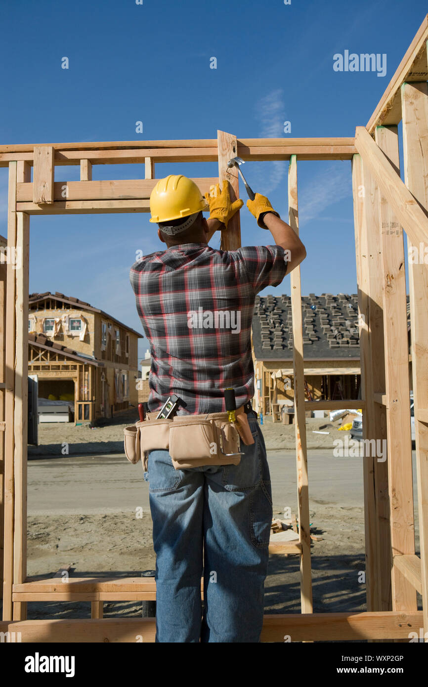 Construction worker hammering nail on construction site Stock Photo - Alamy