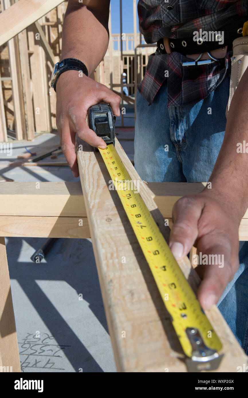 Man measuring half constructed wall with tape measure Stock Photo - Alamy