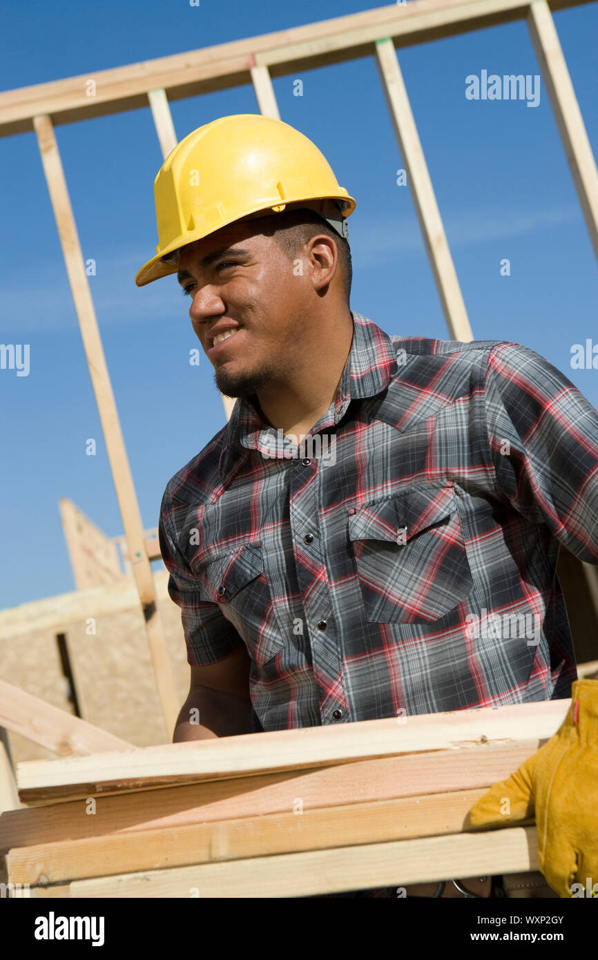 Construction worker carrying planks on construction site Stock Photo ...