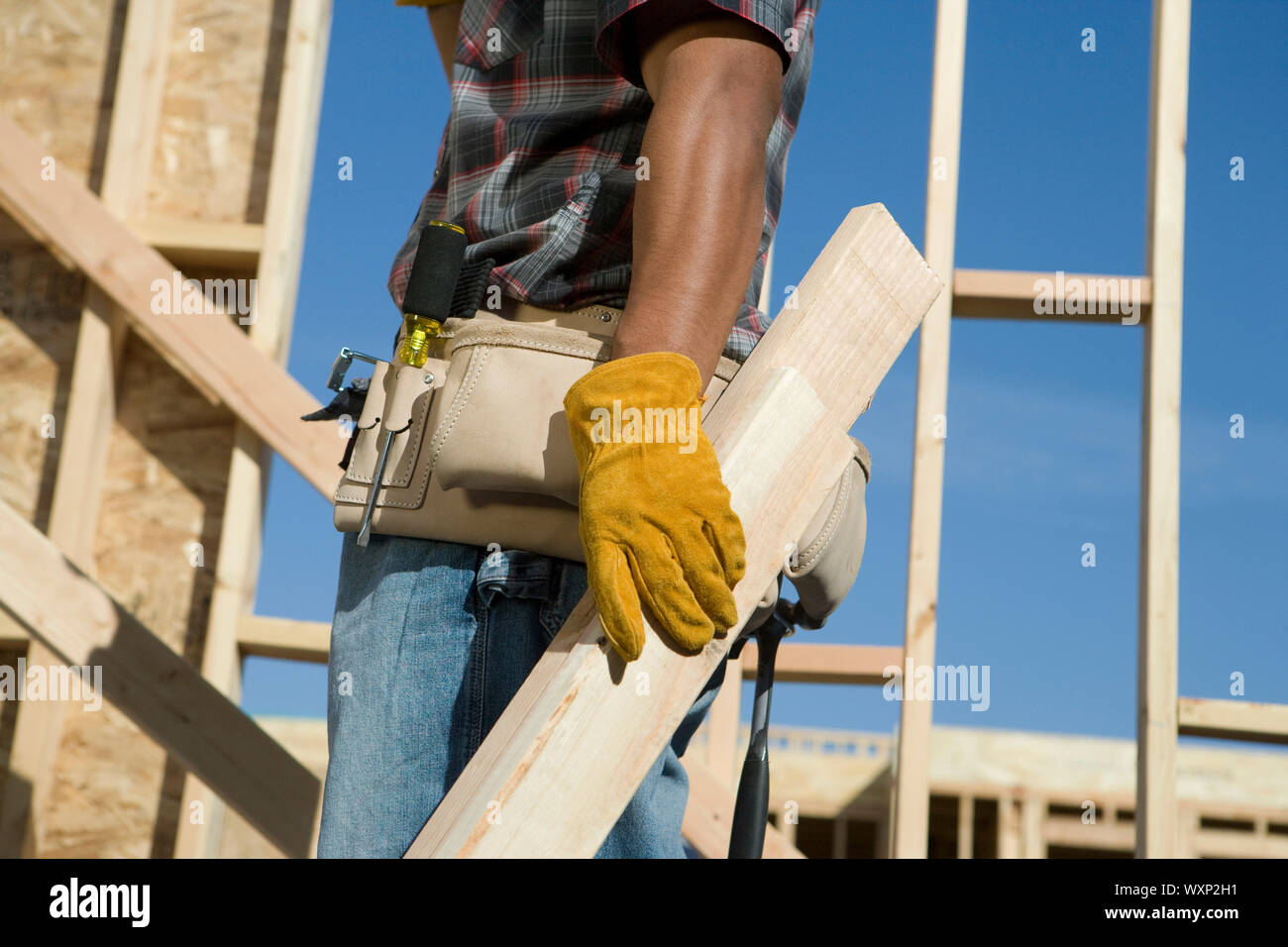 Construction worker carrying planks on construction site Stock Photo ...