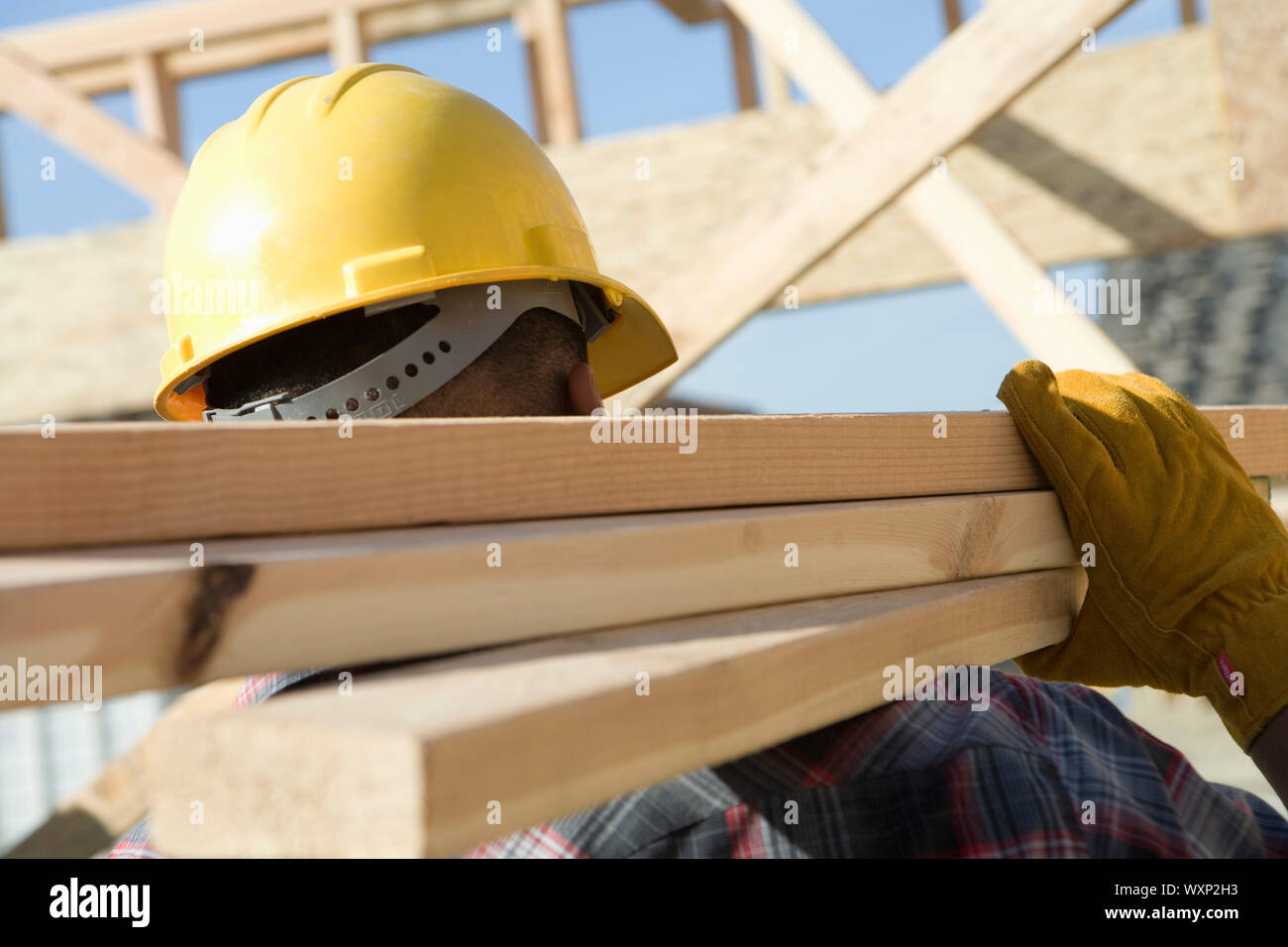 Construction worker carrying planks on construction site Stock Photo ...