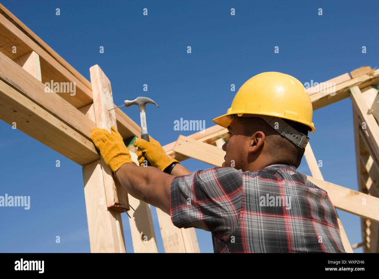 Construction worker hammering nail on construction site Stock Photo - Alamy