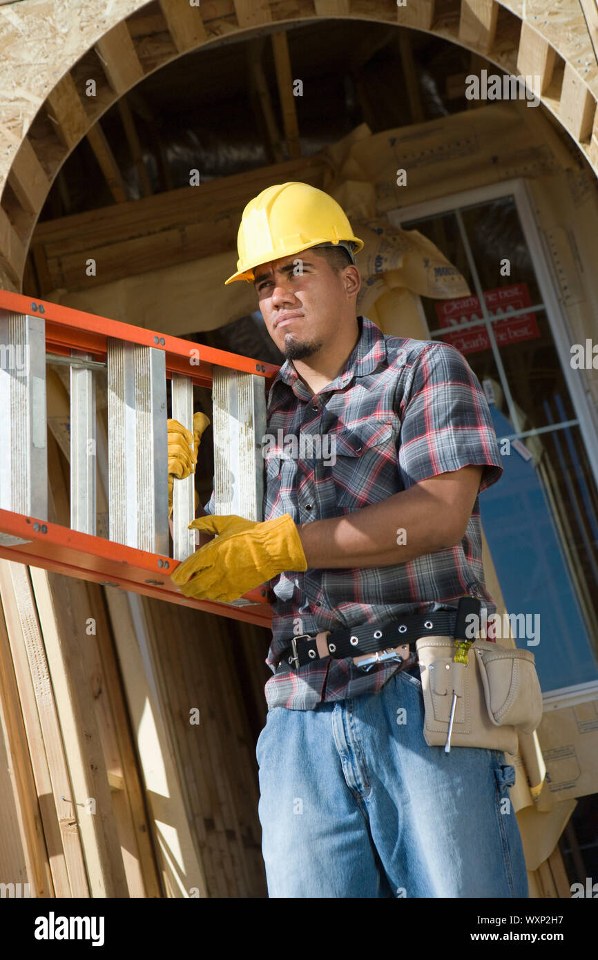 Construction worker carrying step ladder on construction site Stock ...
