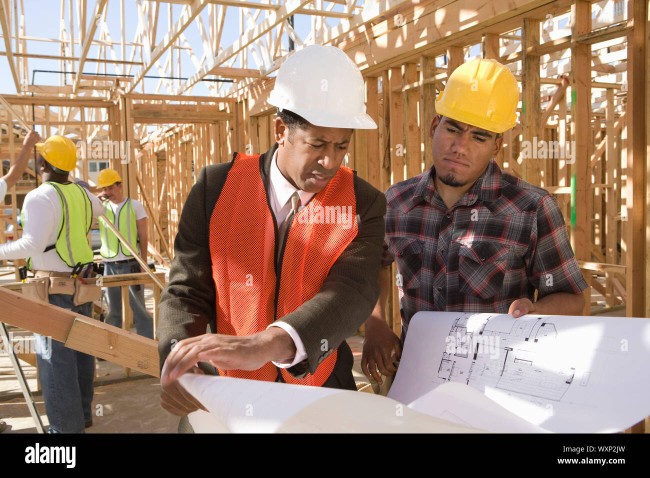 Architect and construction worker looking at blueprints Stock Photo - Alamy