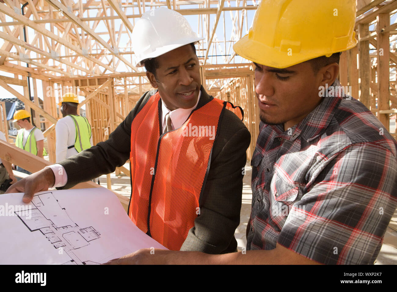 Architect and construction worker looking at blueprints Stock Photo - Alamy