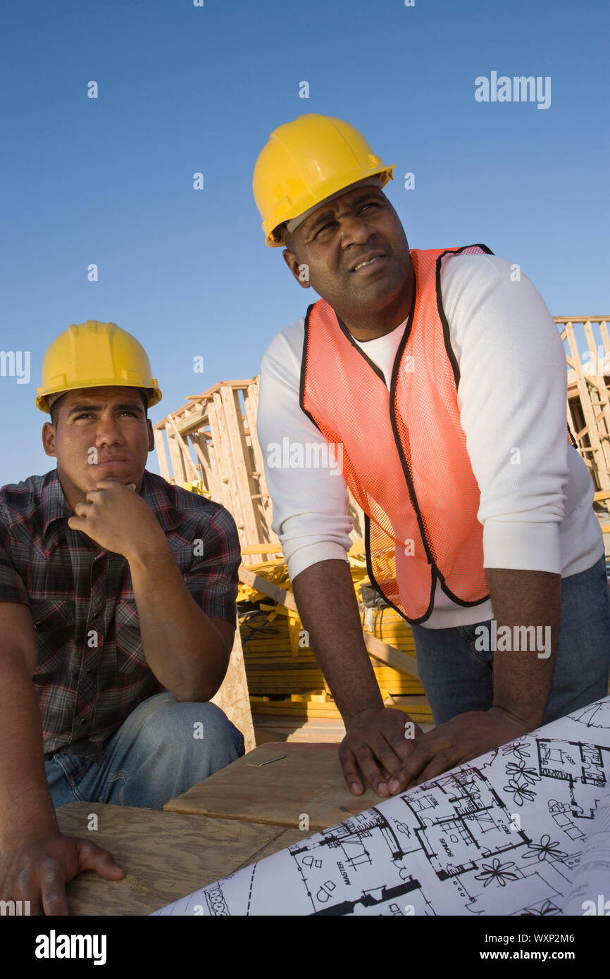 Two construction workers leaning to table with blueprints Stock Photo ...