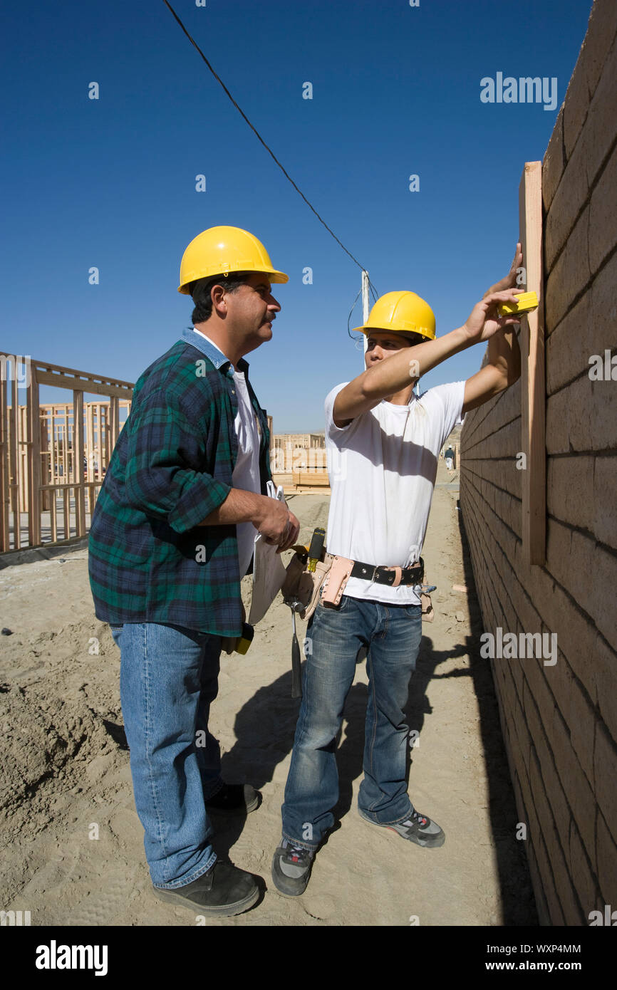 Construction workers measuring brick wall Stock Photo - Alamy