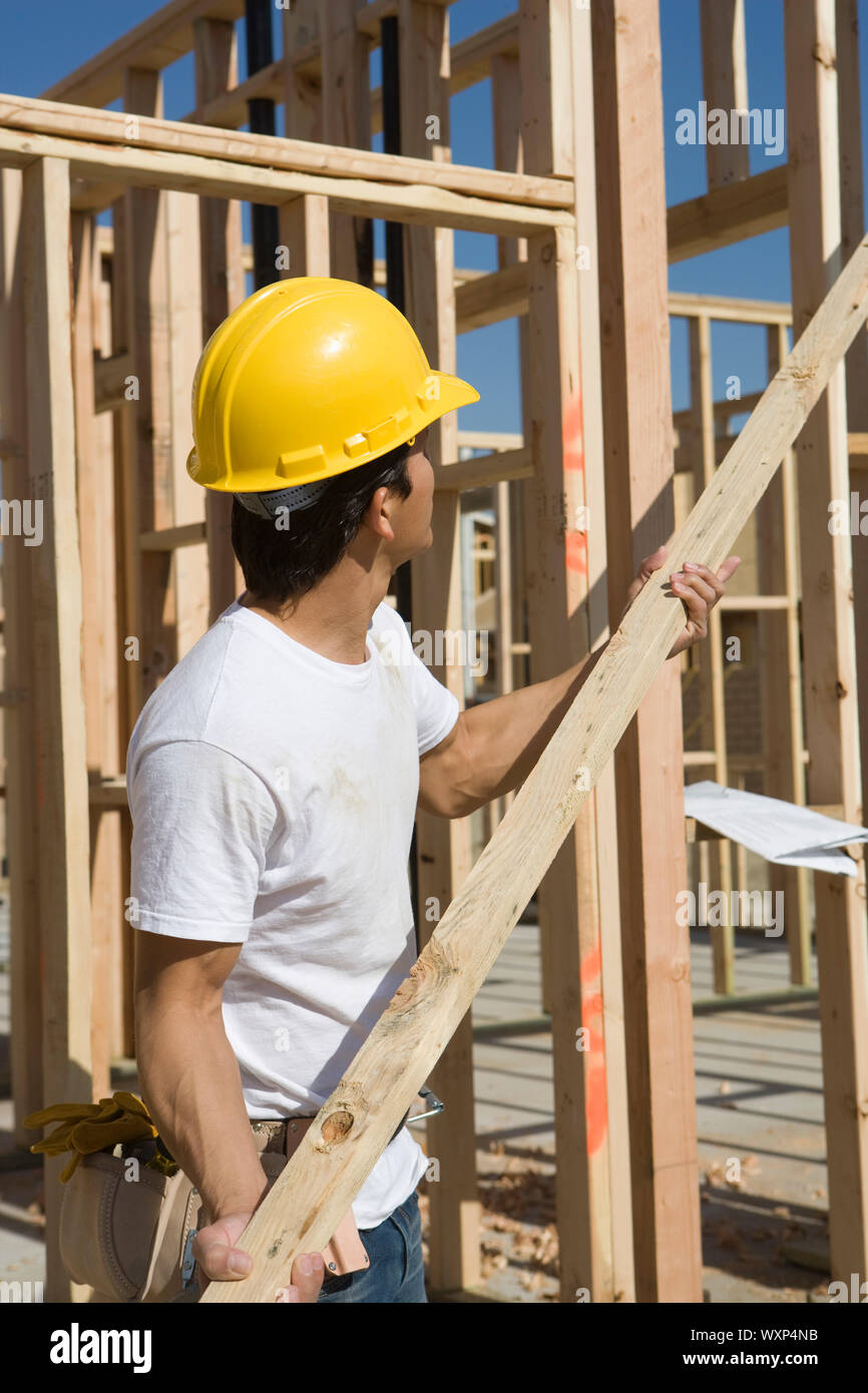 Construction worker holding plank Stock Photo - Alamy