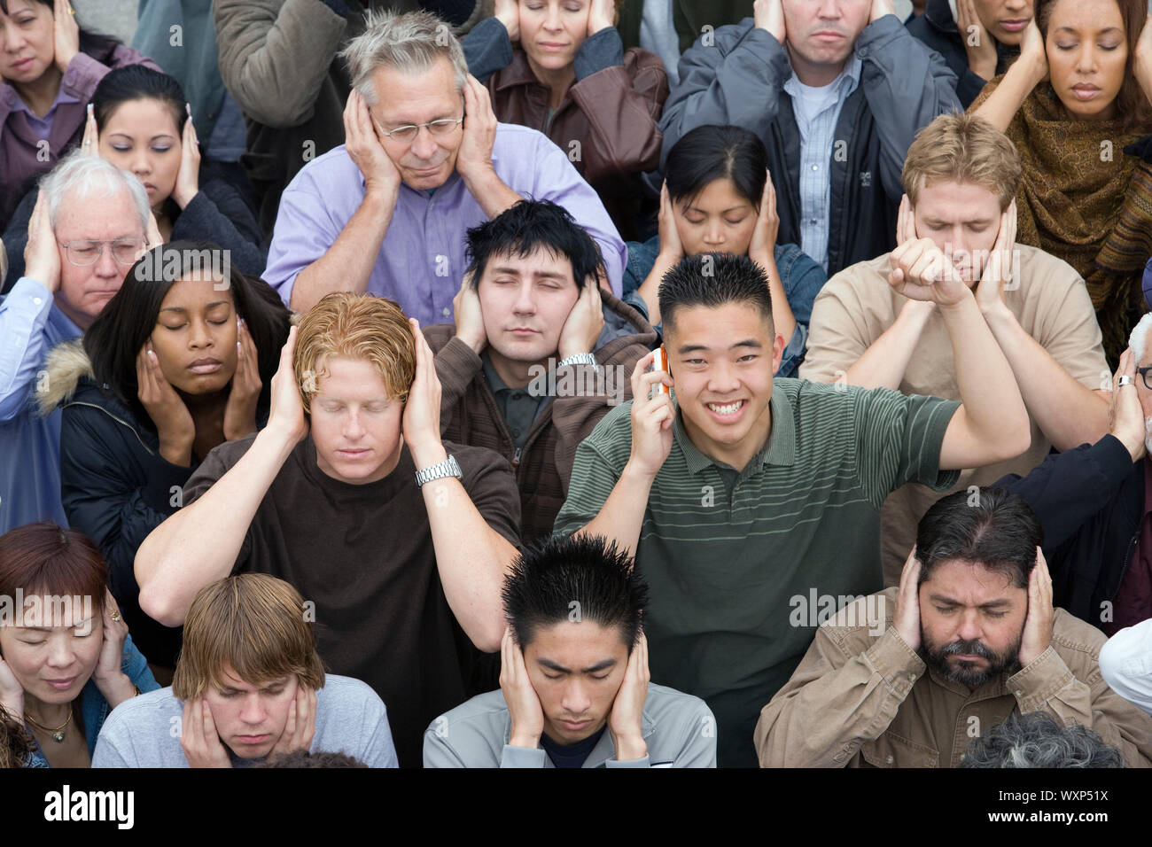 Crowd covering ears Stock Photo - Alamy